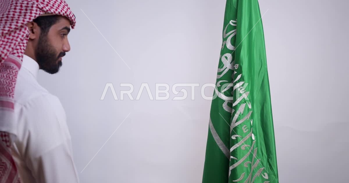 Portrait of a Saudi Arabian Gulf man holding the flag of the Kingdom of ...