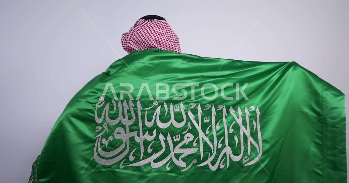 Portrait from the back of a Saudi Arabian Gulf man putting the flag of ...