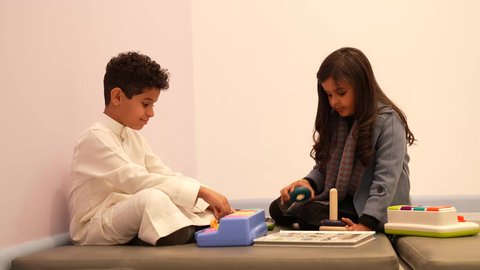 Two Arab Gulf Saudi children wearing traditional attire are sitting ...