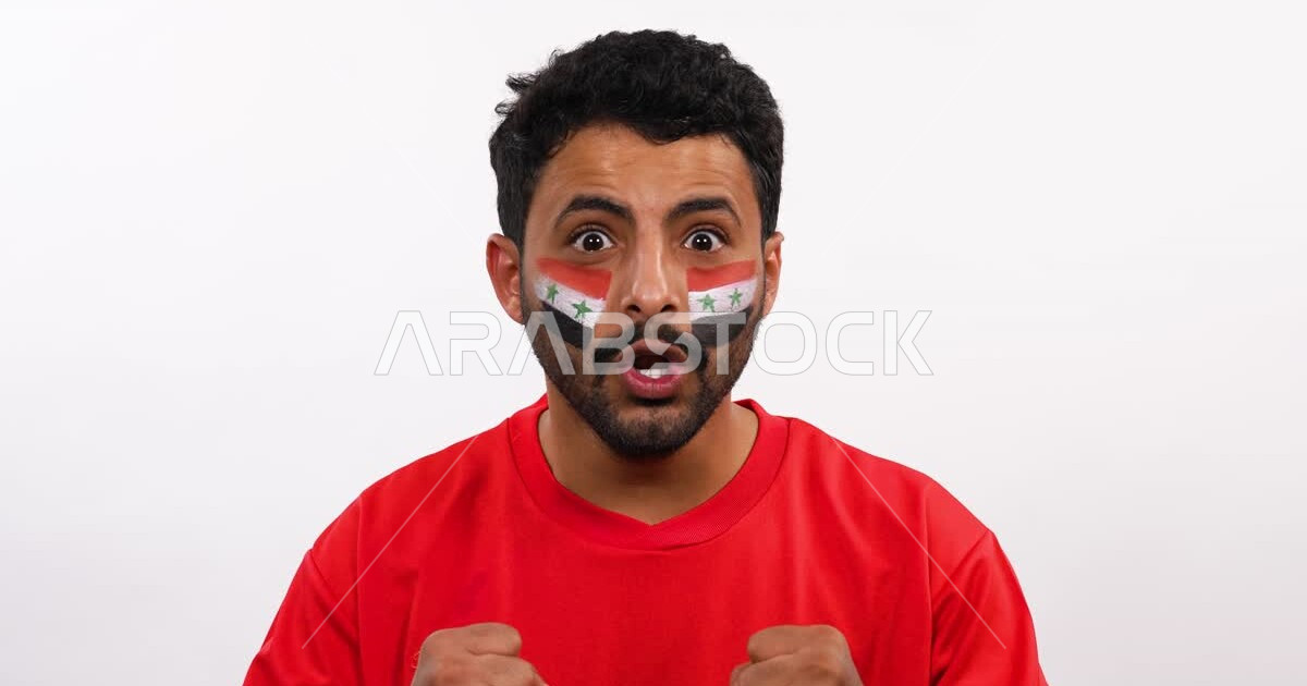 A young Arab Gulf man draws the Syrian flag on his face, encouraging ...