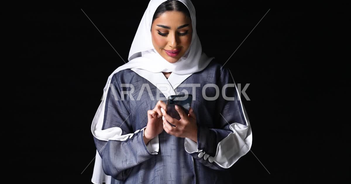 Portrait of a Saudi Arabian Gulf woman using a mobile phone, chatting ...