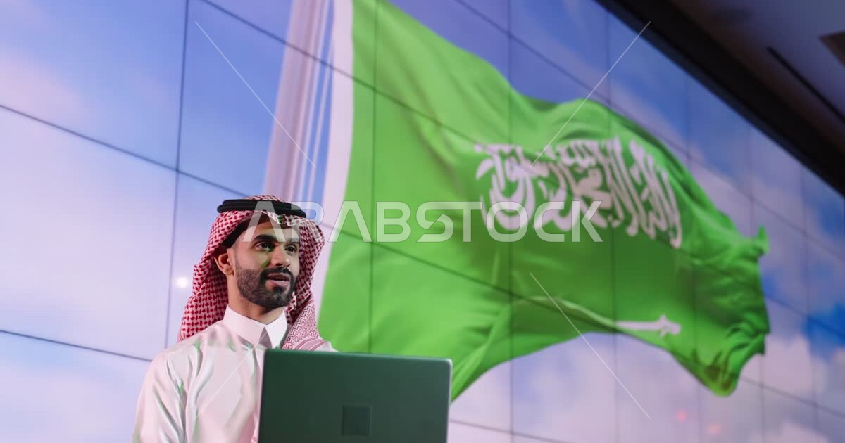A Saudi Arabian Gulf man standing in front of his laptop, background of ...