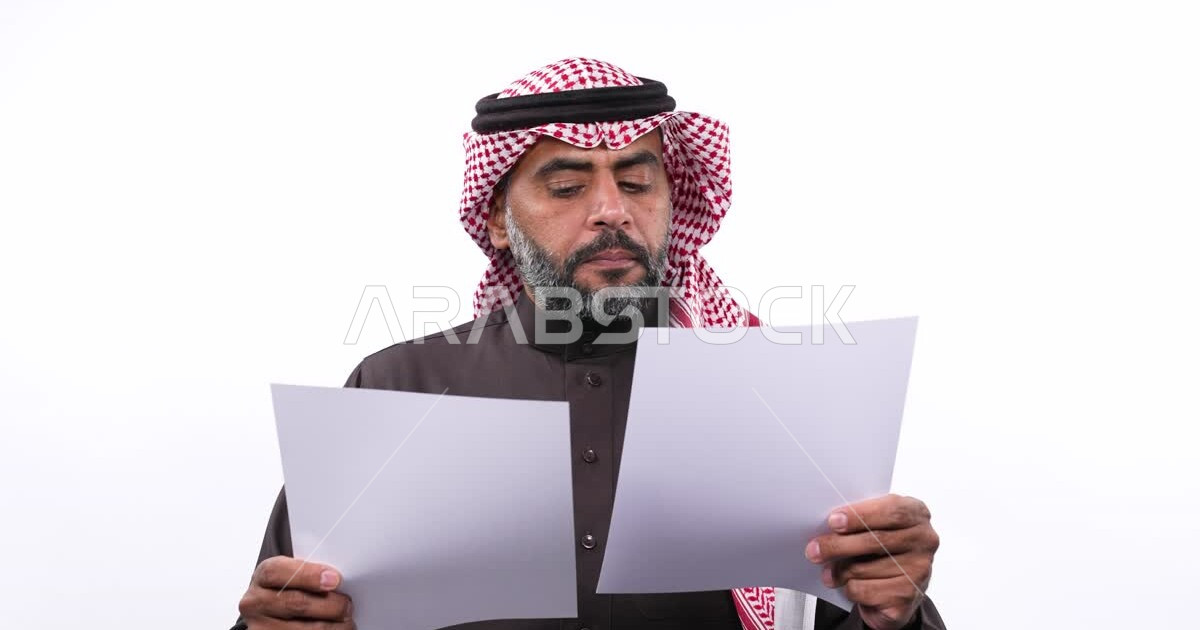 Portrait of a Saudi Arabian Gulf man holding work papers in his hand ...