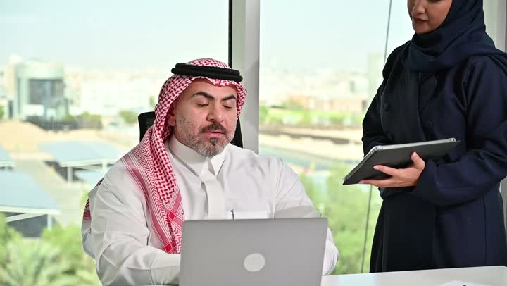 A Saudi Arabian Gulf man in traditional attire is explaining to his ...