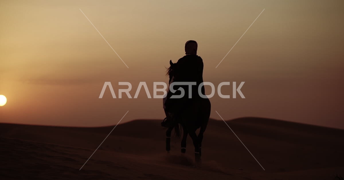 A Saudi Arabian Gulf man riding a horse in the middle of the desert in ...