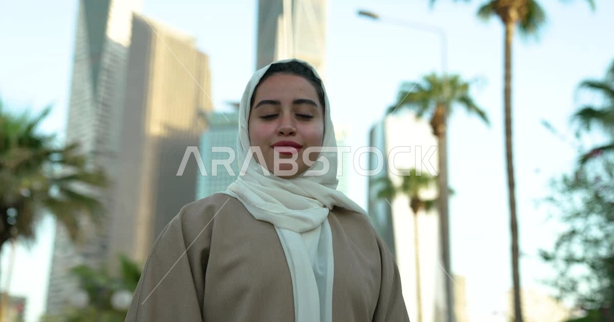 A Saudi Arabian Gulf woman standing in front of the towers of King ...