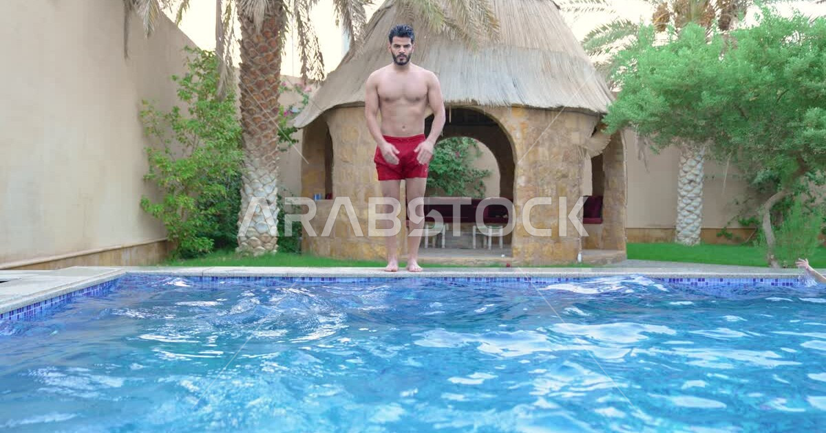 A Saudi Arabian Gulf man jumping into the water pool, recreation and ...