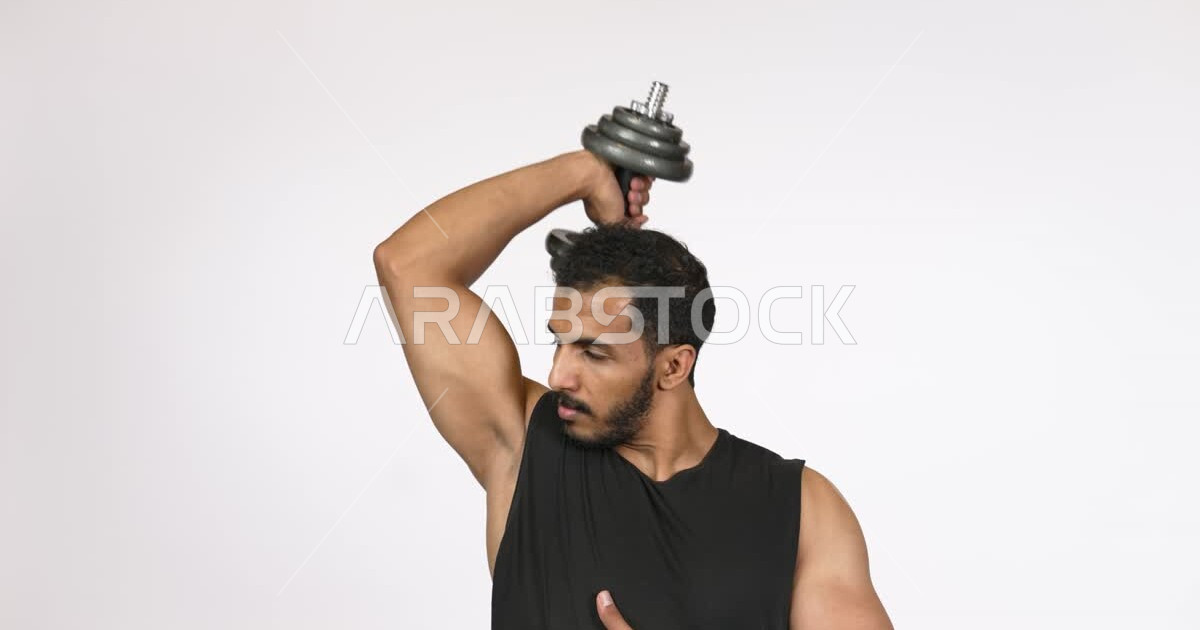 Portrait of a Saudi Arabian Gulf Arab man carrying iron weights in his ...
