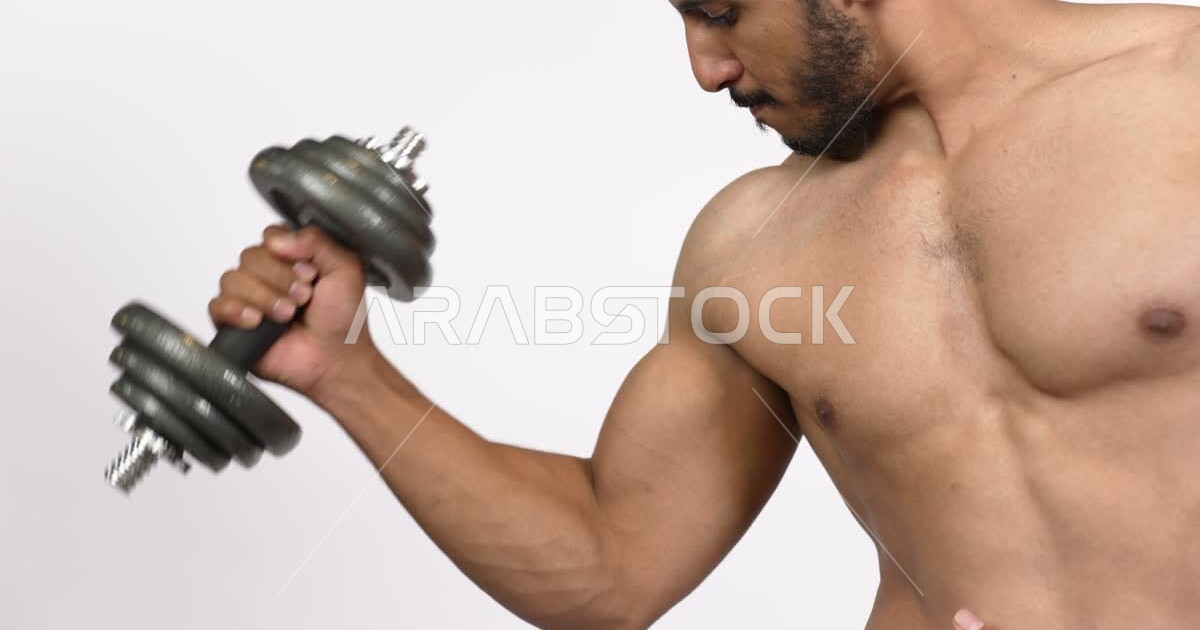 Portrait of a Saudi Arabian Gulf Arab man carrying iron weights in his ...
