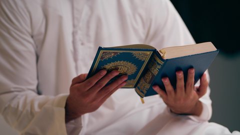 A Saudi Arabian Gulf man wearing traditional attire and a shemagh reads ...