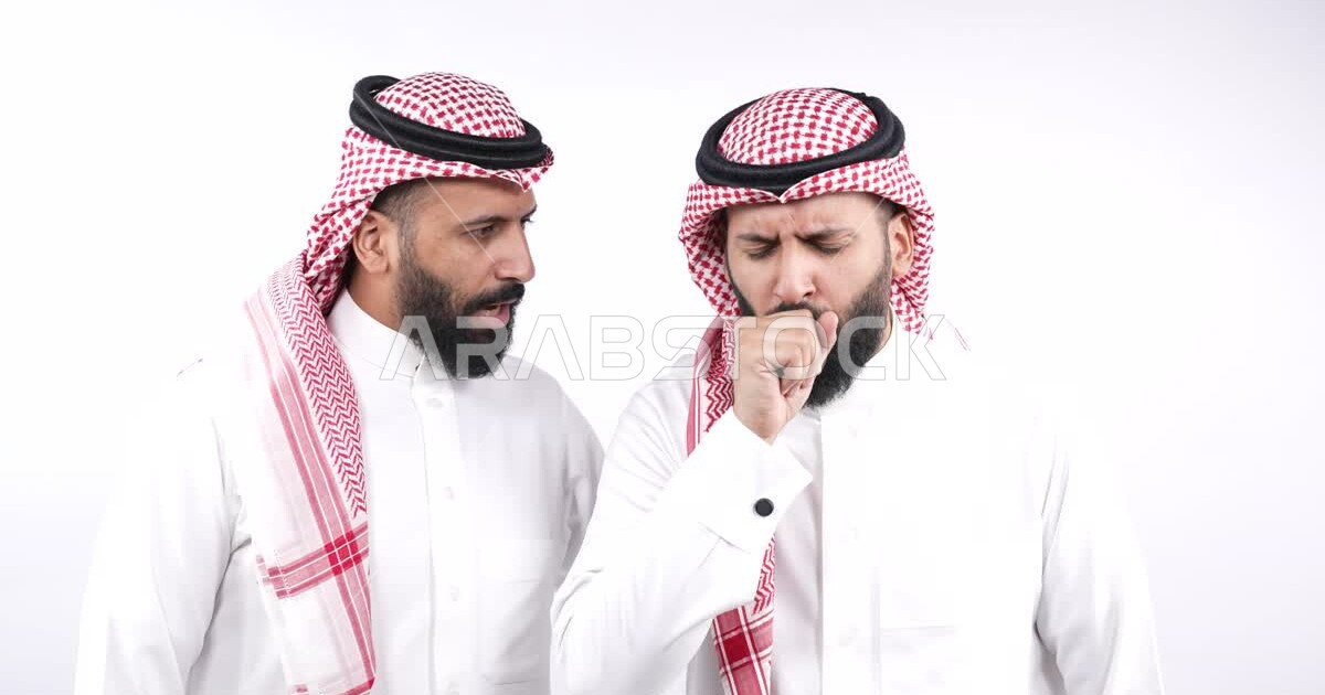 Portrait of two Saudi Arabian Gulf twin men, one of whom puts his hand ...