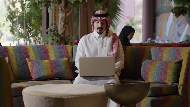 Watching the sunset while riding a bicycle, a young Arab Saudi Gulf man ...