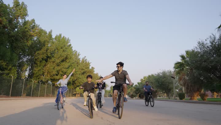 A Gulf Arab Saudi girl wearing casual attire rides a bicycle among the ...