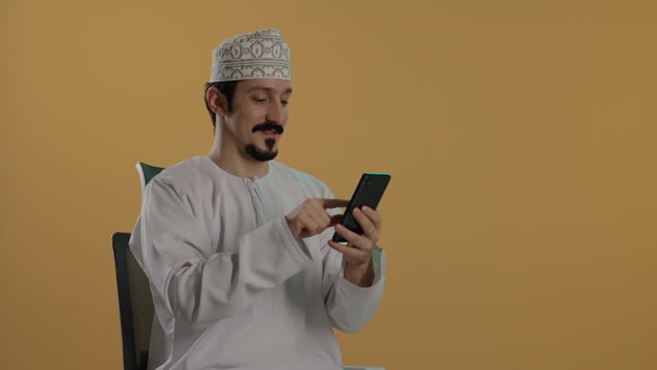 The many uses of the mobile phone, a Gulf Arab Saudi man wearing a ...