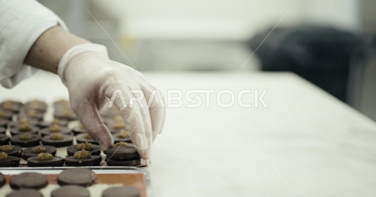 Close-up of a man's hand placing chocolate biscuits on top of each ...