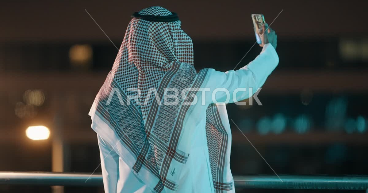 A Saudi Arabian Gulf man using a mobile phone, taking a memorial photo ...