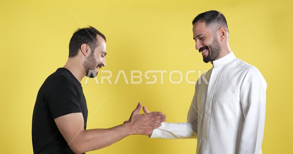Two Gulf Arab Saudi men shake hands with each other, friendship and ...