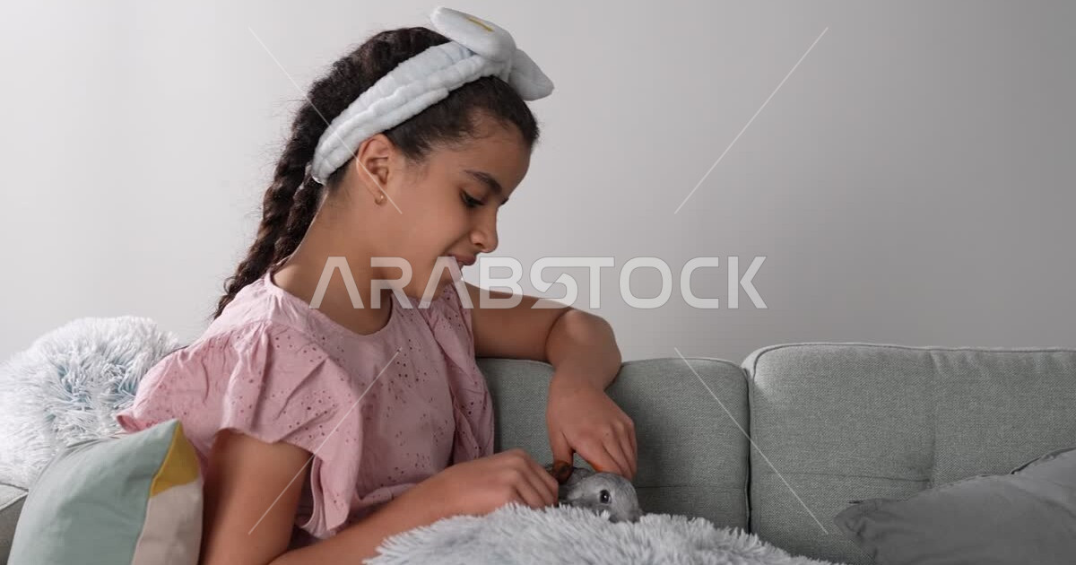 Saudi Arabian Gulf girl with pet rabbit at home, fun and playing with ...