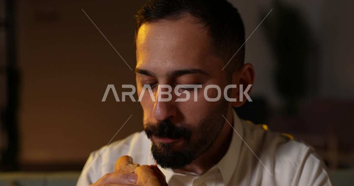 A Saudi Arabian Gulf man eating a burger sandwich, eating fast food ...