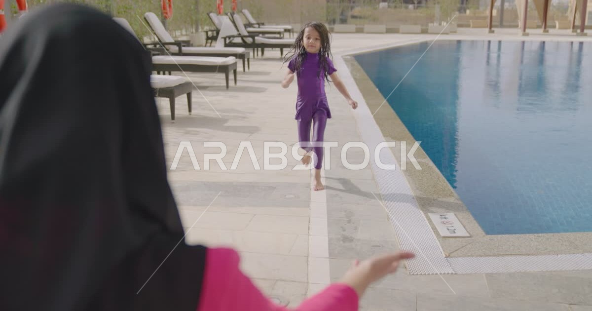 A Saudi Arabian Gulf girl wearing a swimsuit and running towards her ...