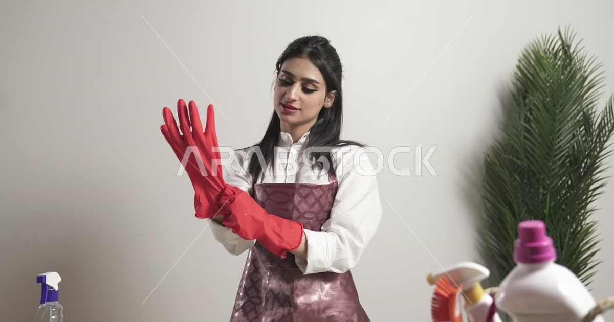 A Saudi Arabian Gulf woman, using medical cleaning gloves and wiping ...