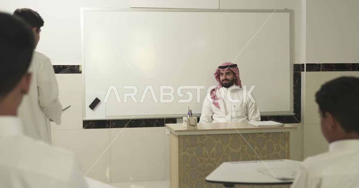 A Saudi Arabian Gulf teacher sitting on a chair with the white school ...