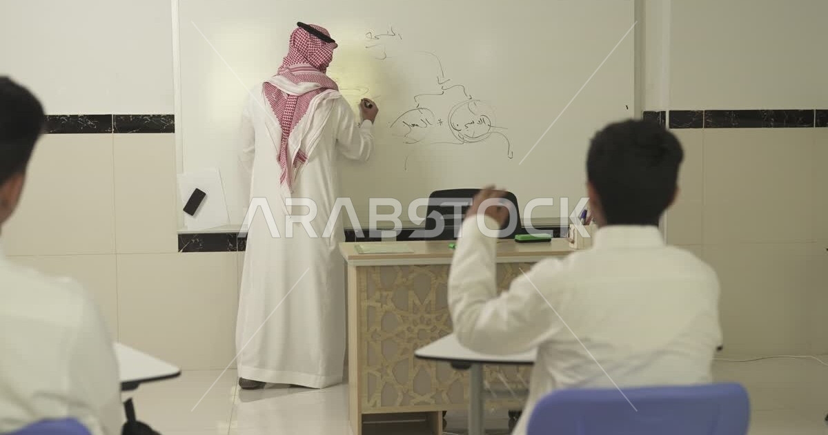 A Saudi Arabian Gulf teacher explaining the lesson on the white board ...