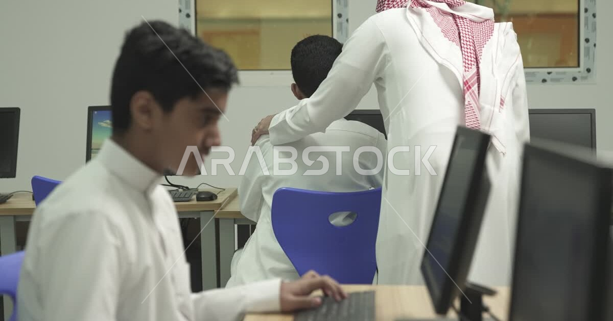 A Saudi Arabian Gulf teacher in the computer lab, teaching students how ...