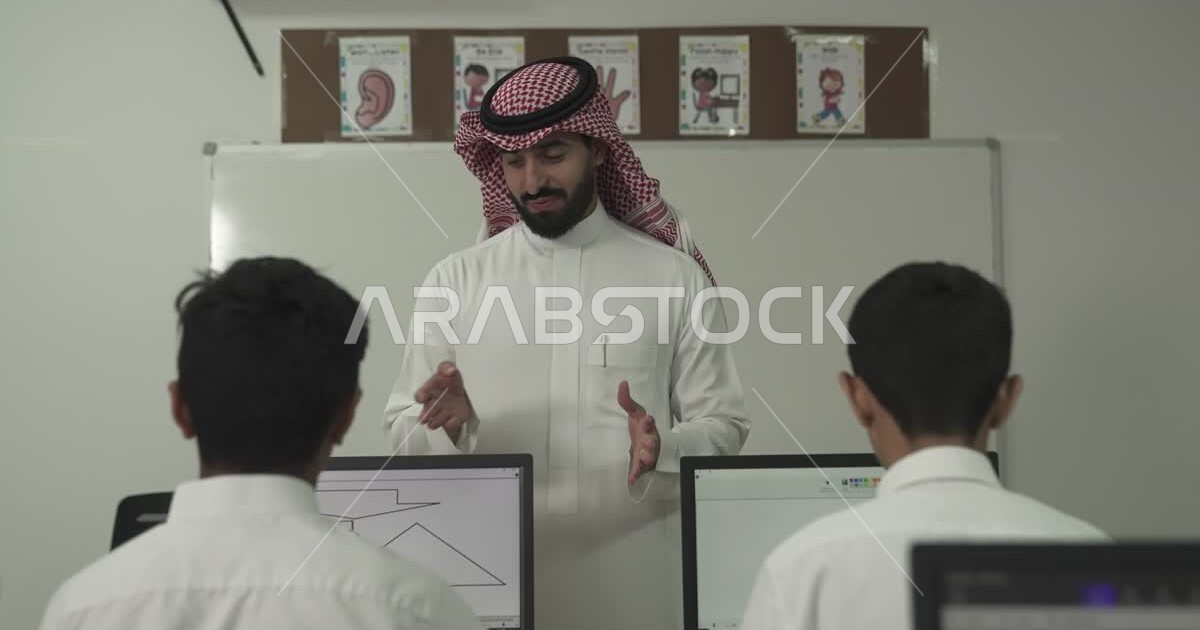 A Saudi Arabian Gulf teacher in the computer lab, teaching students how ...