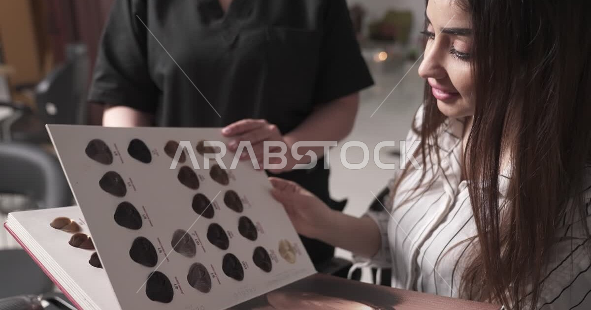 A Saudi Arabian Gulf woman in a women's beauty salon, choosing the ...