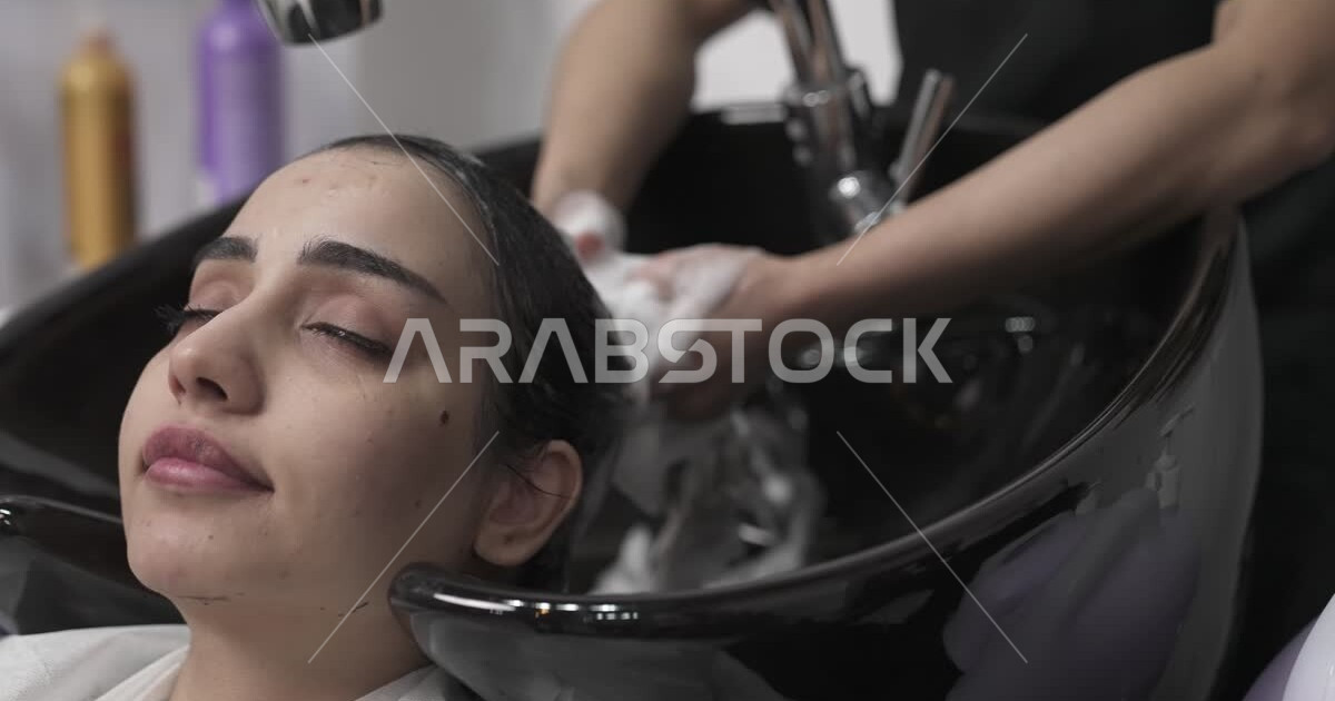 A Saudi Arabian Gulf woman in a women’s beauty salon, a hairdresser who ...
