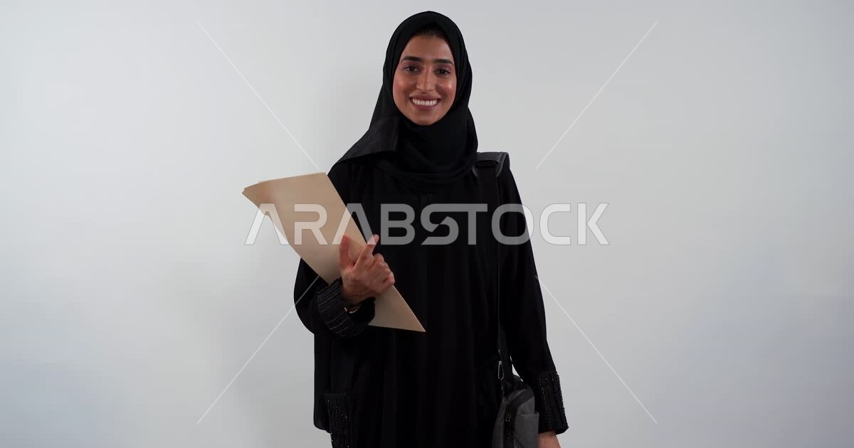 Portrait of a veiled Saudi Arab university student holding a university ...