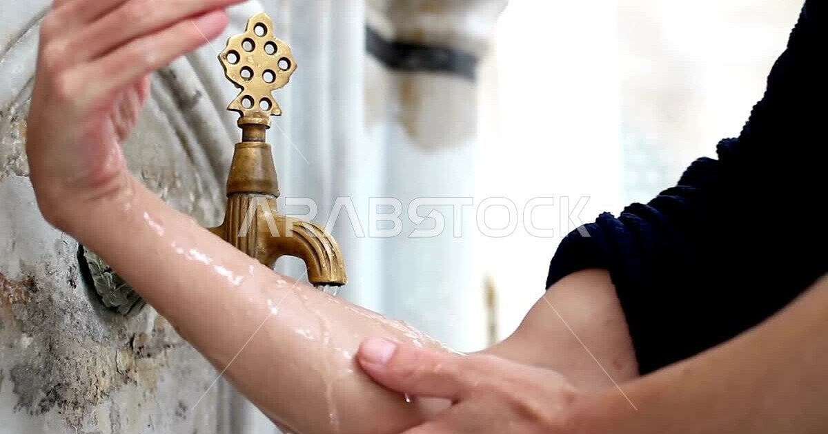 Close-up of a young Muslim man washing his arms with water, tap water ...