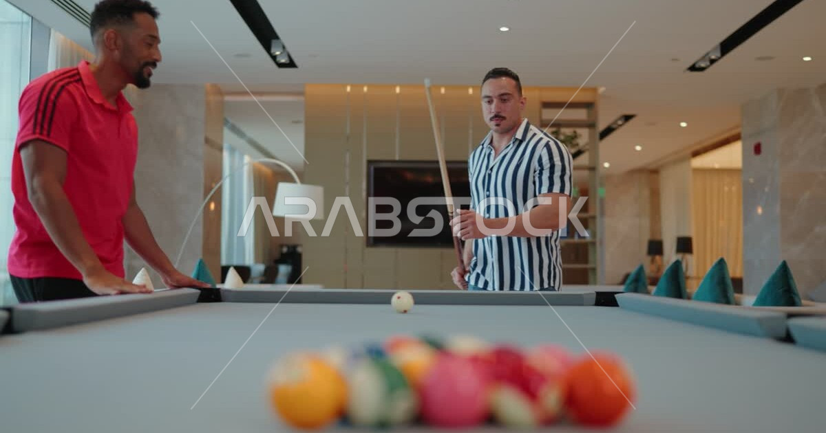 A group of Saudi Arabian Gulf friends playing billiards, recreational ...