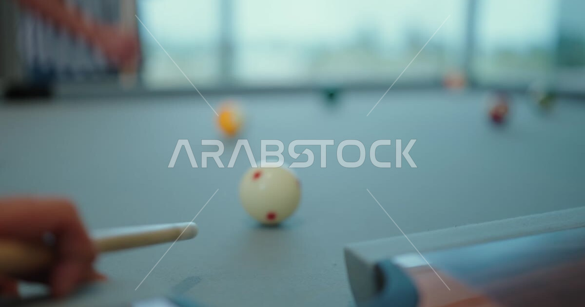 A group of Saudi Arabian Gulf friends playing billiards, recreational ...