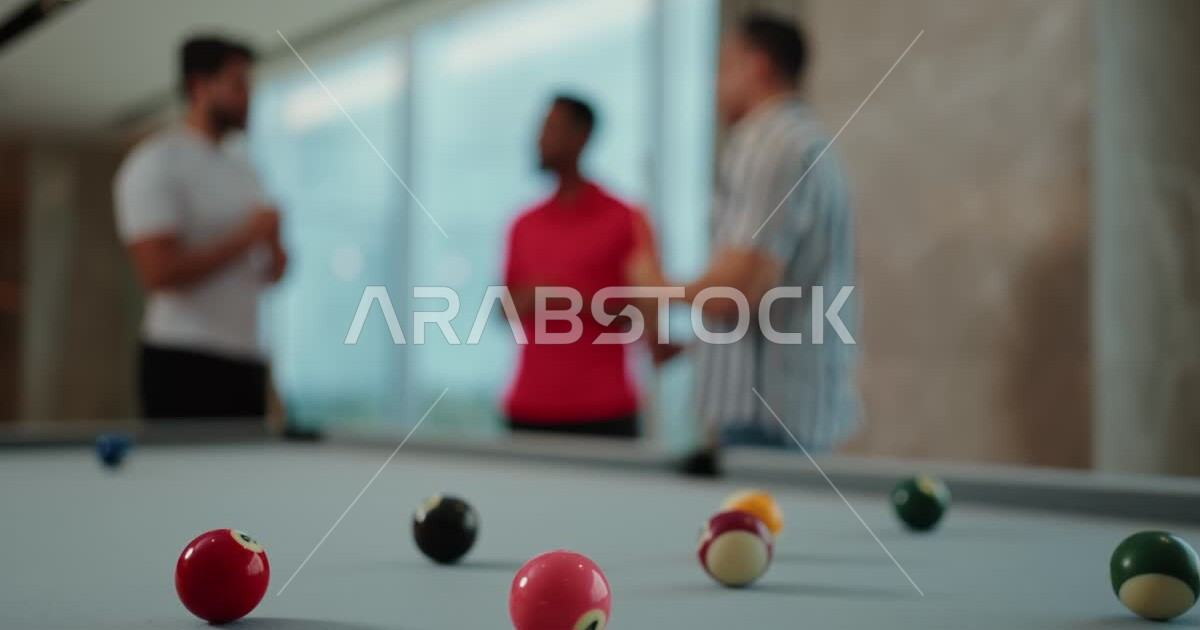 A group of Saudi Arabian Gulf friends playing billiards, recreational ...