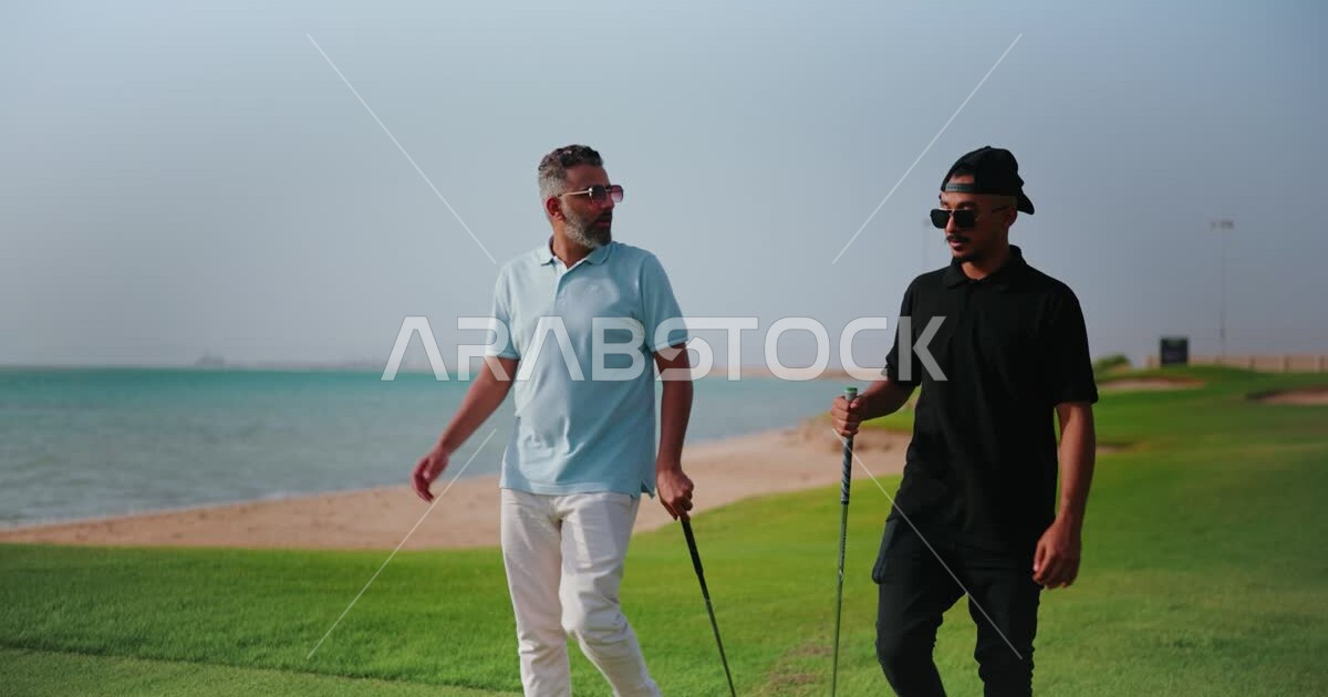 Two Gulf Arab men wearing sports uniforms, playing golf on large green ...