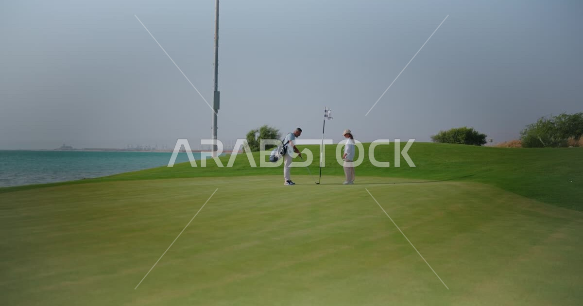A Saudi Arabian Gulf man and woman wearing sports uniforms, playing ...