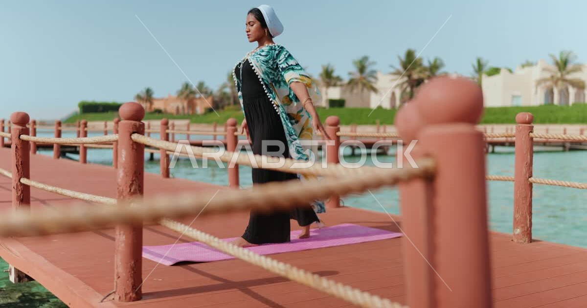 A Saudi Arabian Gulf woman on an enjoyable summer trip, practicing yoga ...