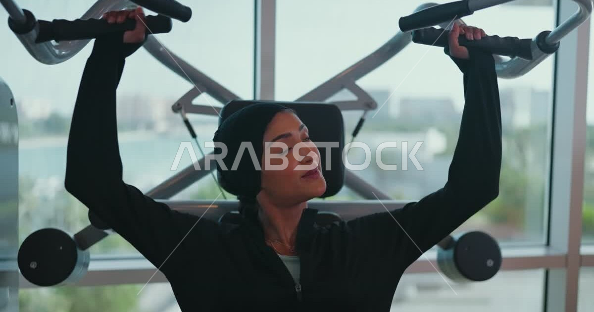 A Saudi Arabian Gulf woman wears sports clothes and exercises using ...