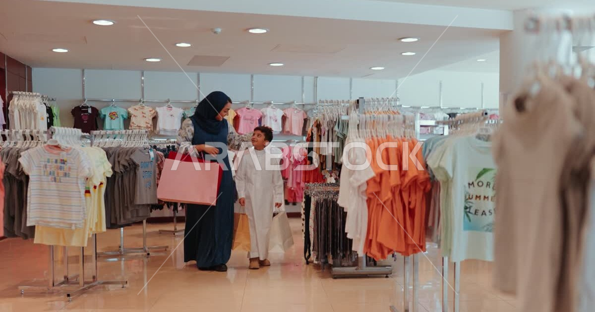 An Arab Saudi Gulf family shopping from clothing stores, enjoying ...
