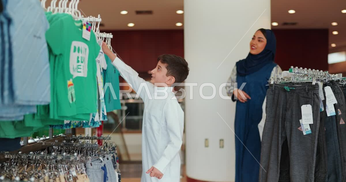 An Arab Saudi Gulf family shopping from clothing stores, enjoying ...