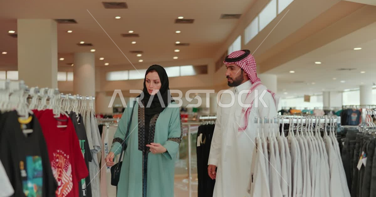 A Saudi Gulf Arab couple shopping in a clothing store, enjoying ...