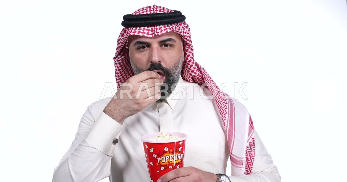 Portrait of a Saudi Arabian Gulf man enjoying eating popcorn, popcorn ...