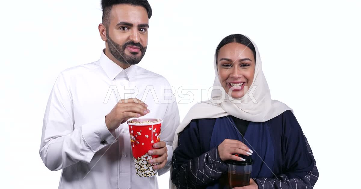 Portrait of a Saudi Arabian Gulf couple enjoying eating popcorn ...