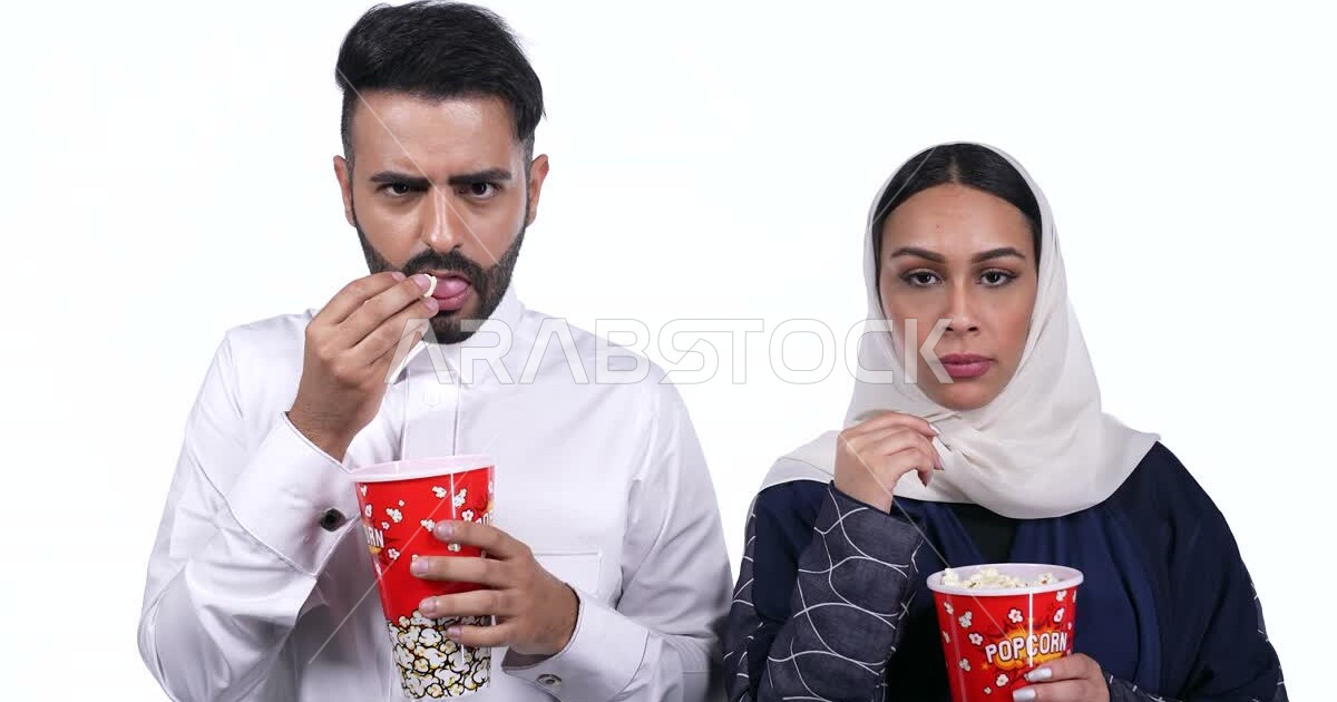 Portrait of a Saudi Arab Gulf couple enjoying eating popcorn, popcorn ...
