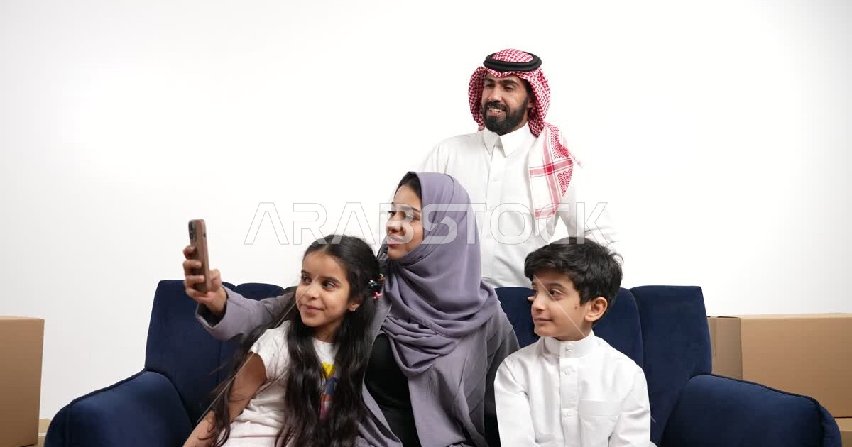 Portrait of a Saudi Arabian Gulf family sitting on the sofa, moving to ...