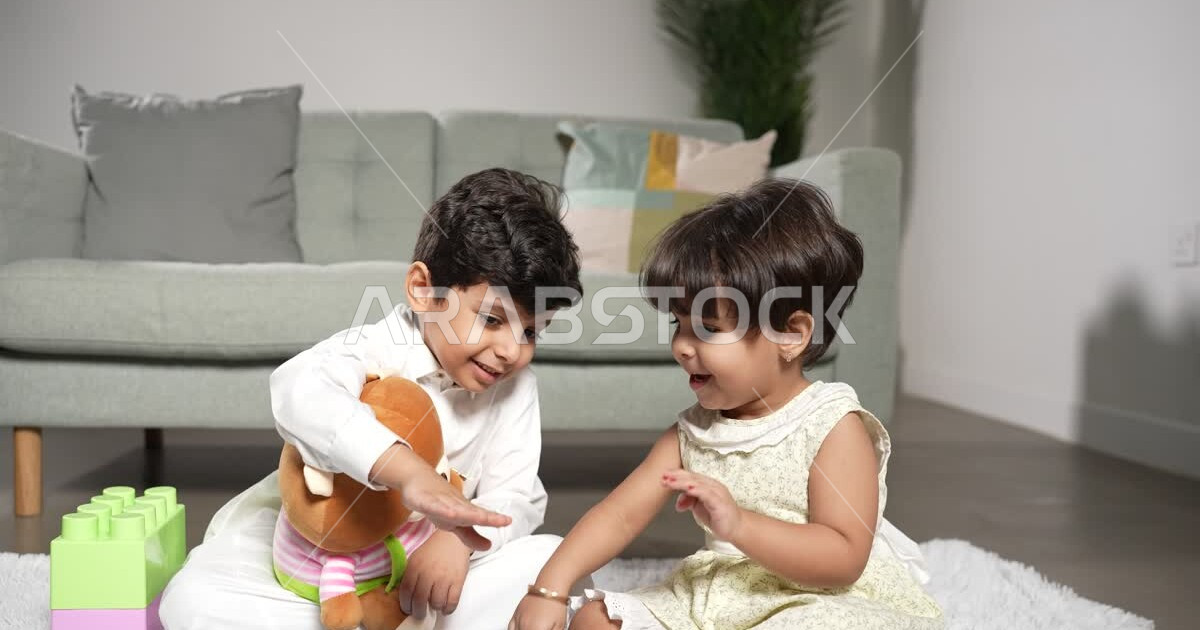 Two Saudi Arabian Gulf children in the living room, playing with ...