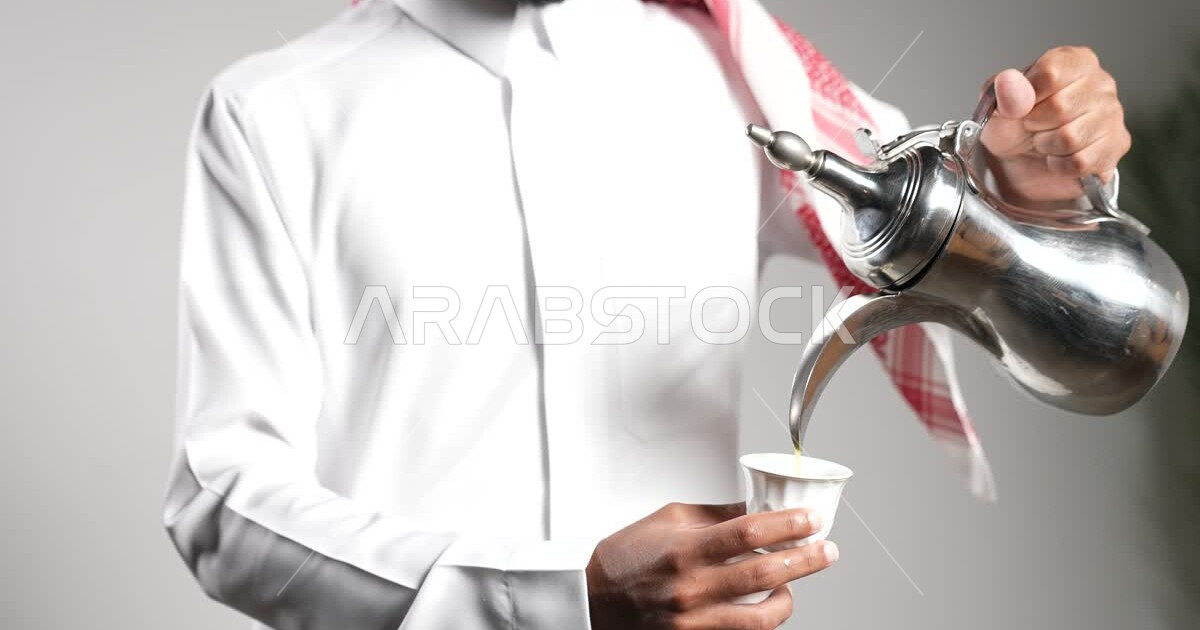A Saudi Arabian Gulf man wearing a traditional Saudi dress pouring ...
