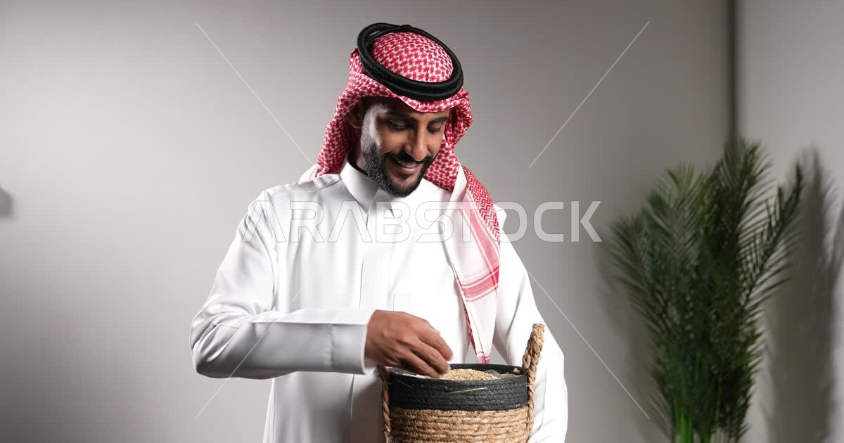 A Saudi Arabian Gulf man wearing traditional Saudi dress carries in his ...